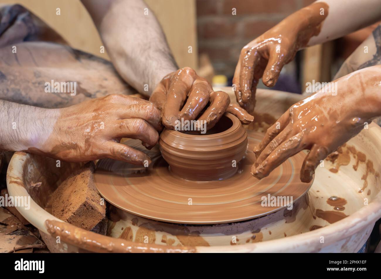 hands of a master potter and a child making dishes. A lesson in a ...