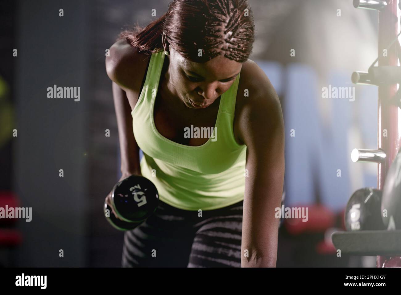 Building the body she deserves. a young woman lifting weights at the ...