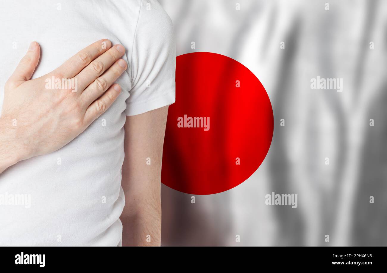 Japanese person with hand on heart on the background of Japan flag ...