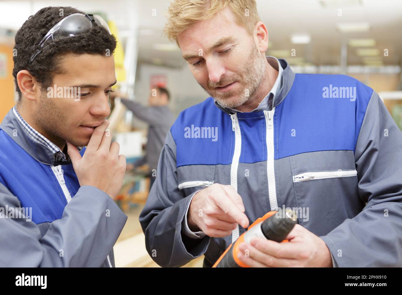 foreman overseeing apprentice using drill on wall Stock Photo - Alamy