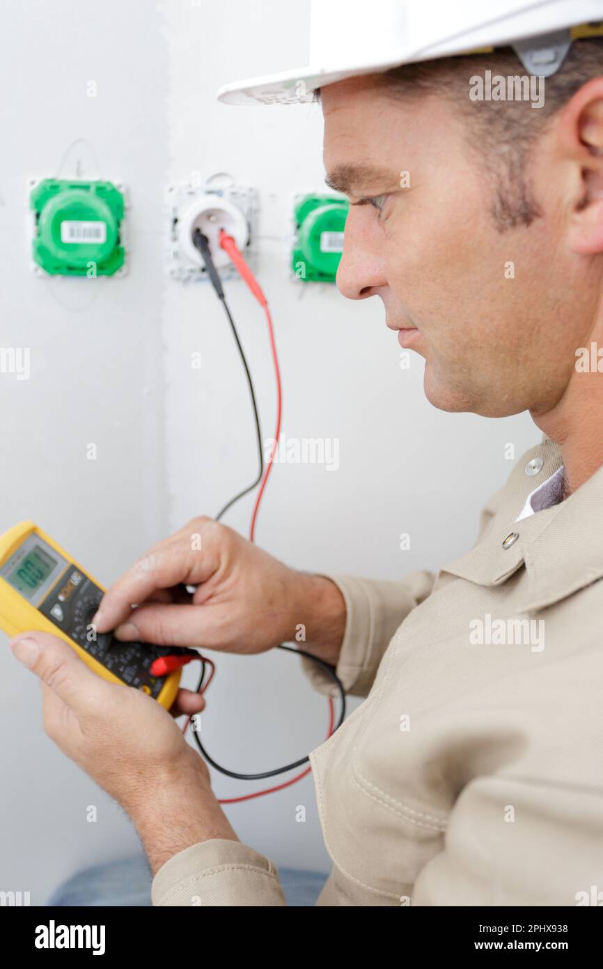 electrician measuring voltage of socket in new building Stock Photo - Alamy