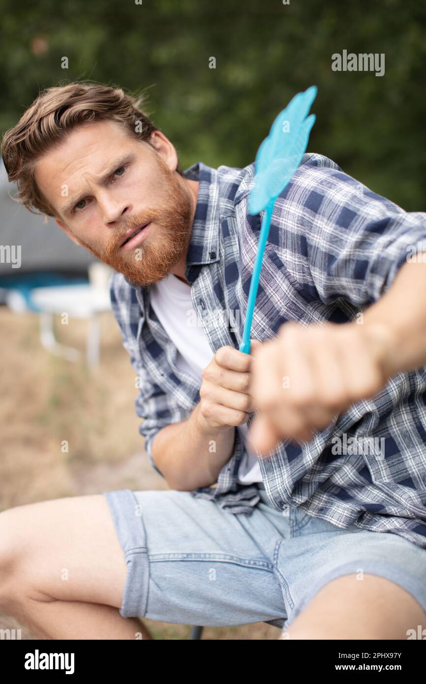 man on a camping try to kill mosquito Stock Photo - Alamy