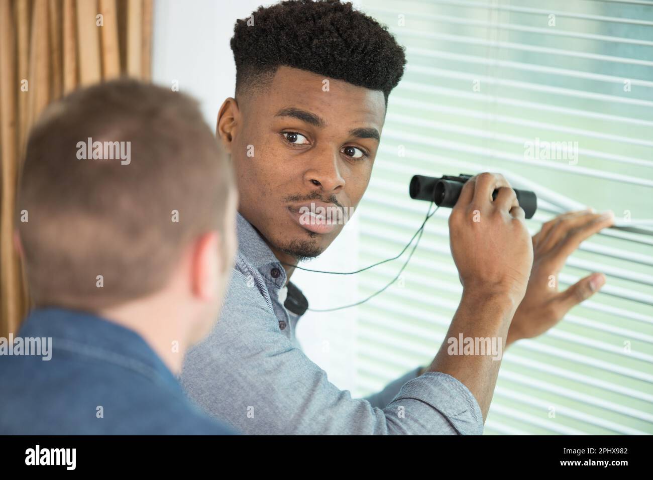 young men look out the window through binoculars Stock Photo - Alamy