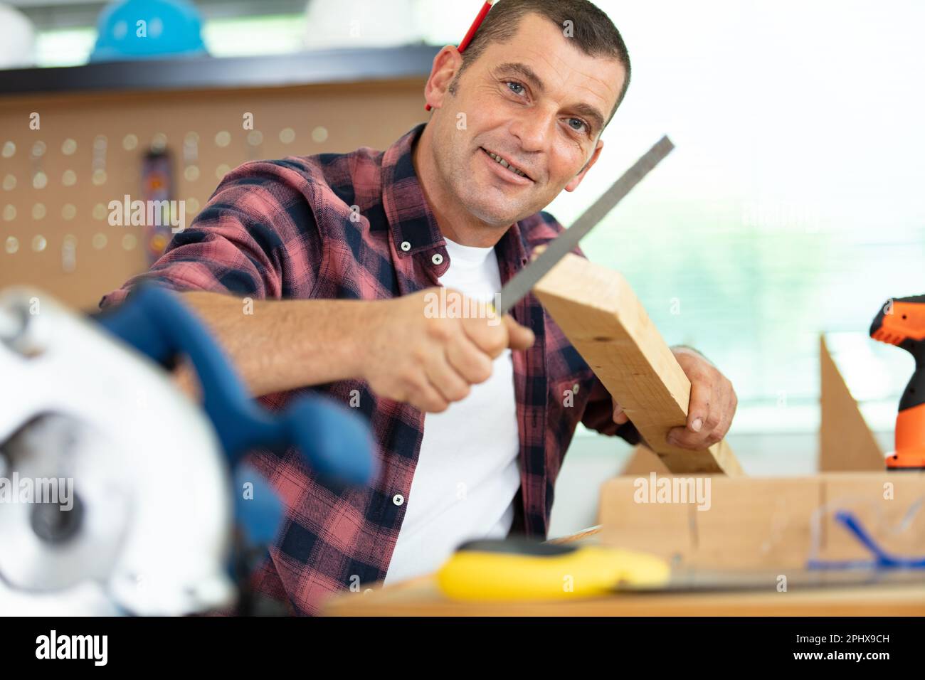 man using abrasive file on a length of wood Stock Photo - Alamy