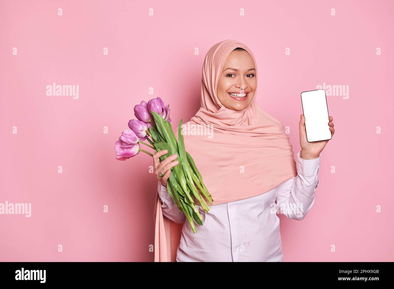Gorgeous Middle-Eastern Muslim woman in pink hijab, showing at camera a ...