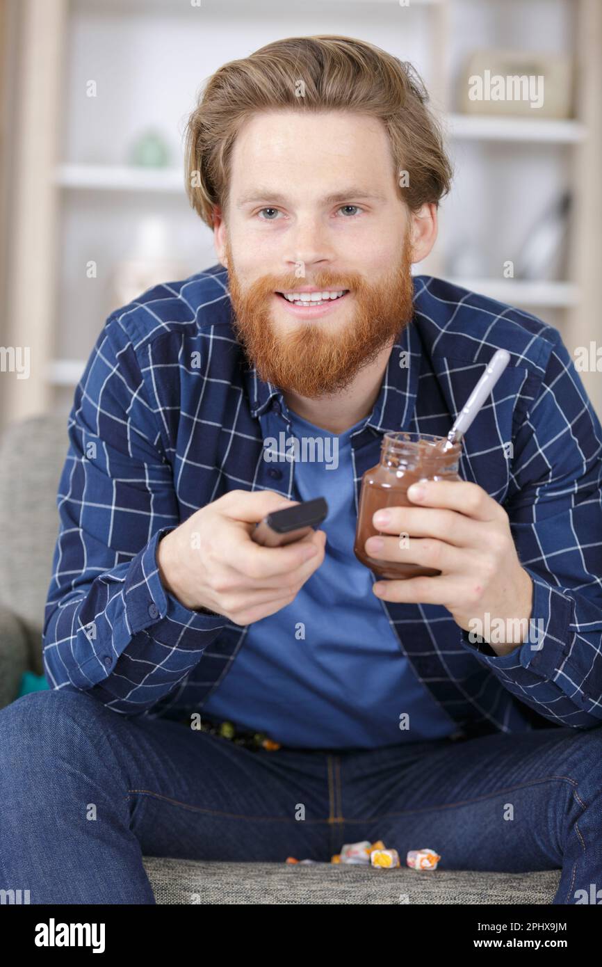 man eating sugary snacks while watching tv Stock Photo - Alamy