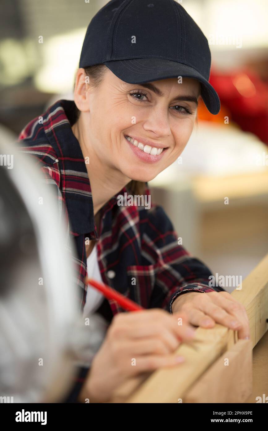pretty carpenter woman is marking on wood for cut Stock Photo - Alamy
