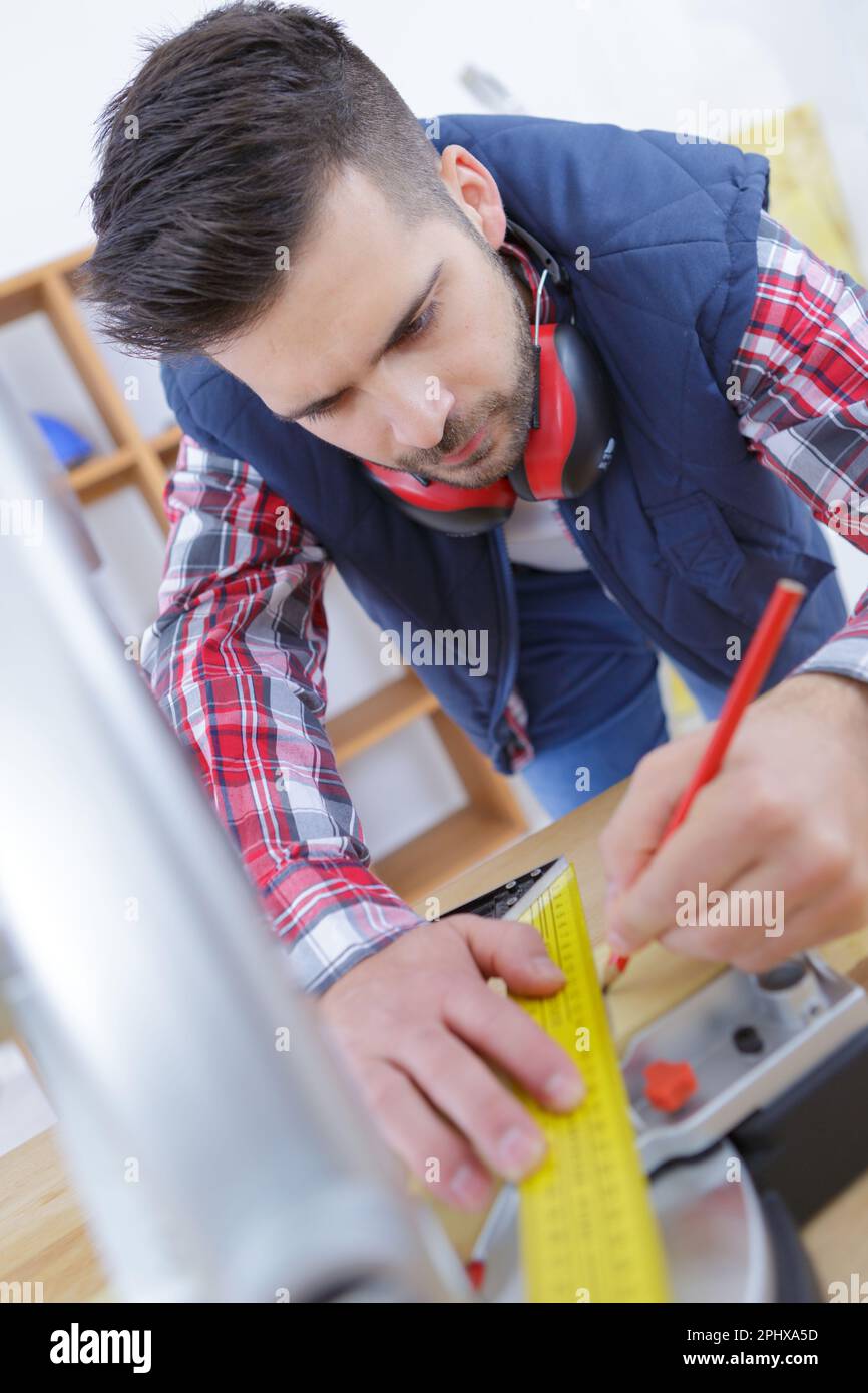 handsome carpenter is measuring wood Stock Photo - Alamy