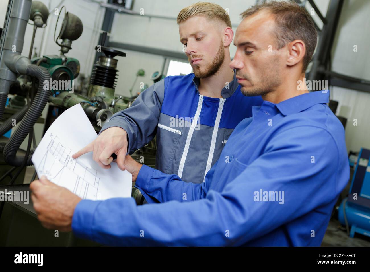 men in factory looking at paperwork Stock Photo - Alamy