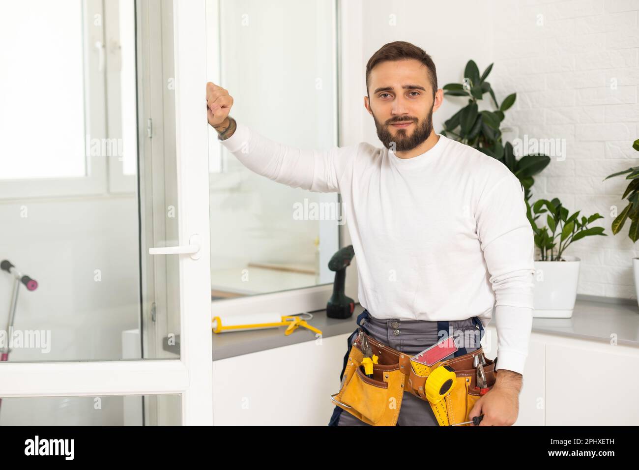handsome young man installing bay window in a new house construction ...