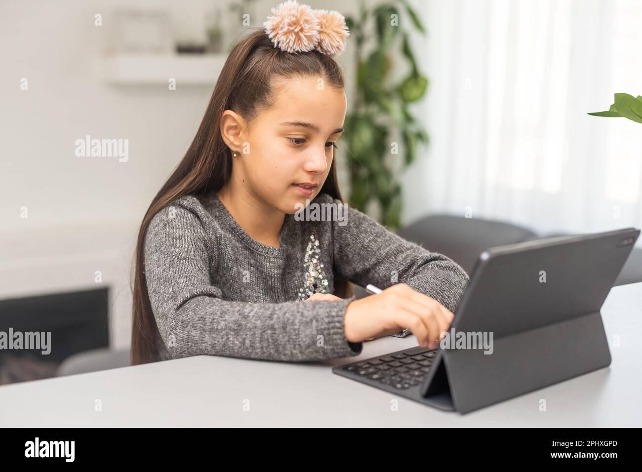 school kid girl student using digital tablet looking at screen at desk ...