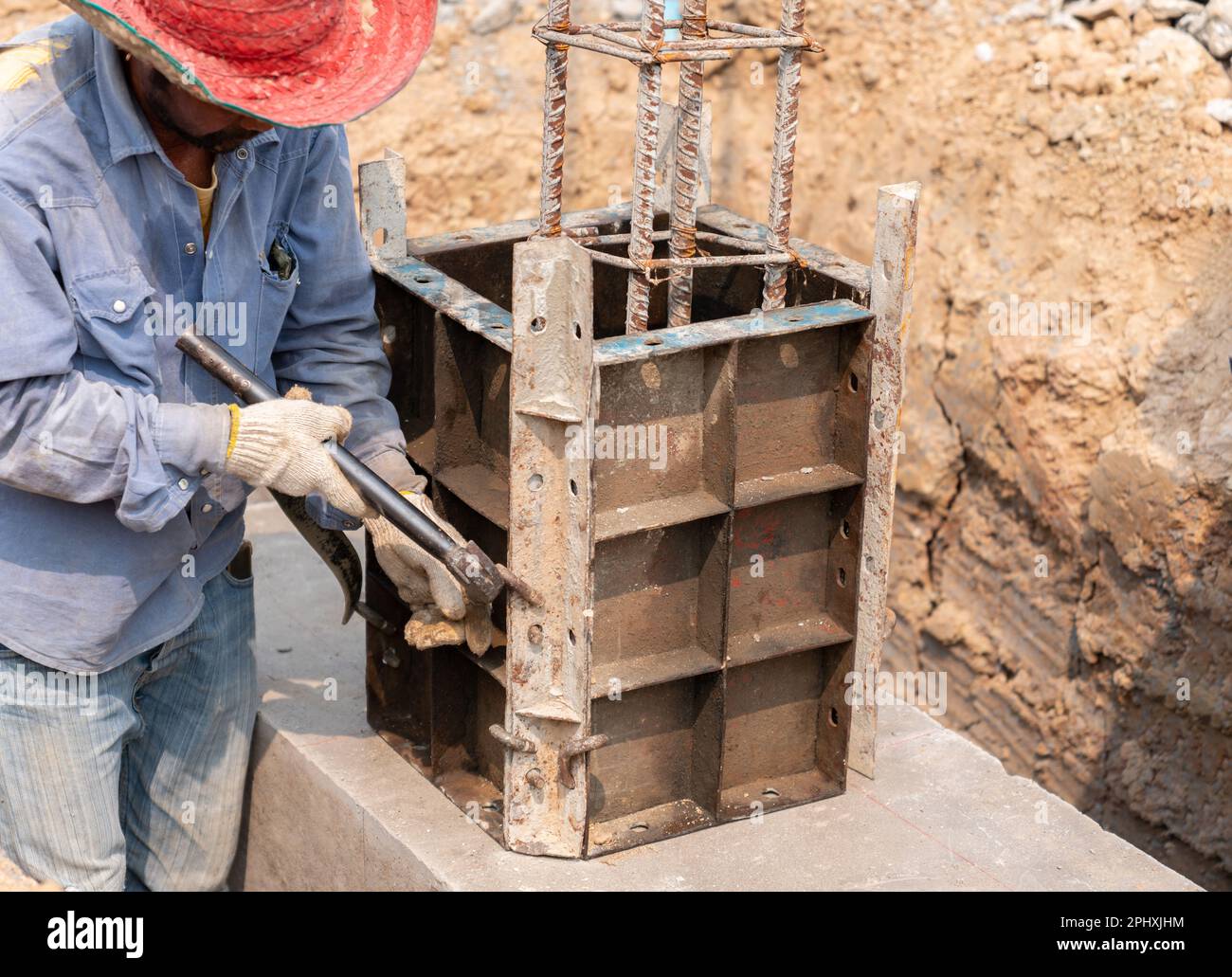 The man assembly formwork for pour concrete pole with hammer in ...
