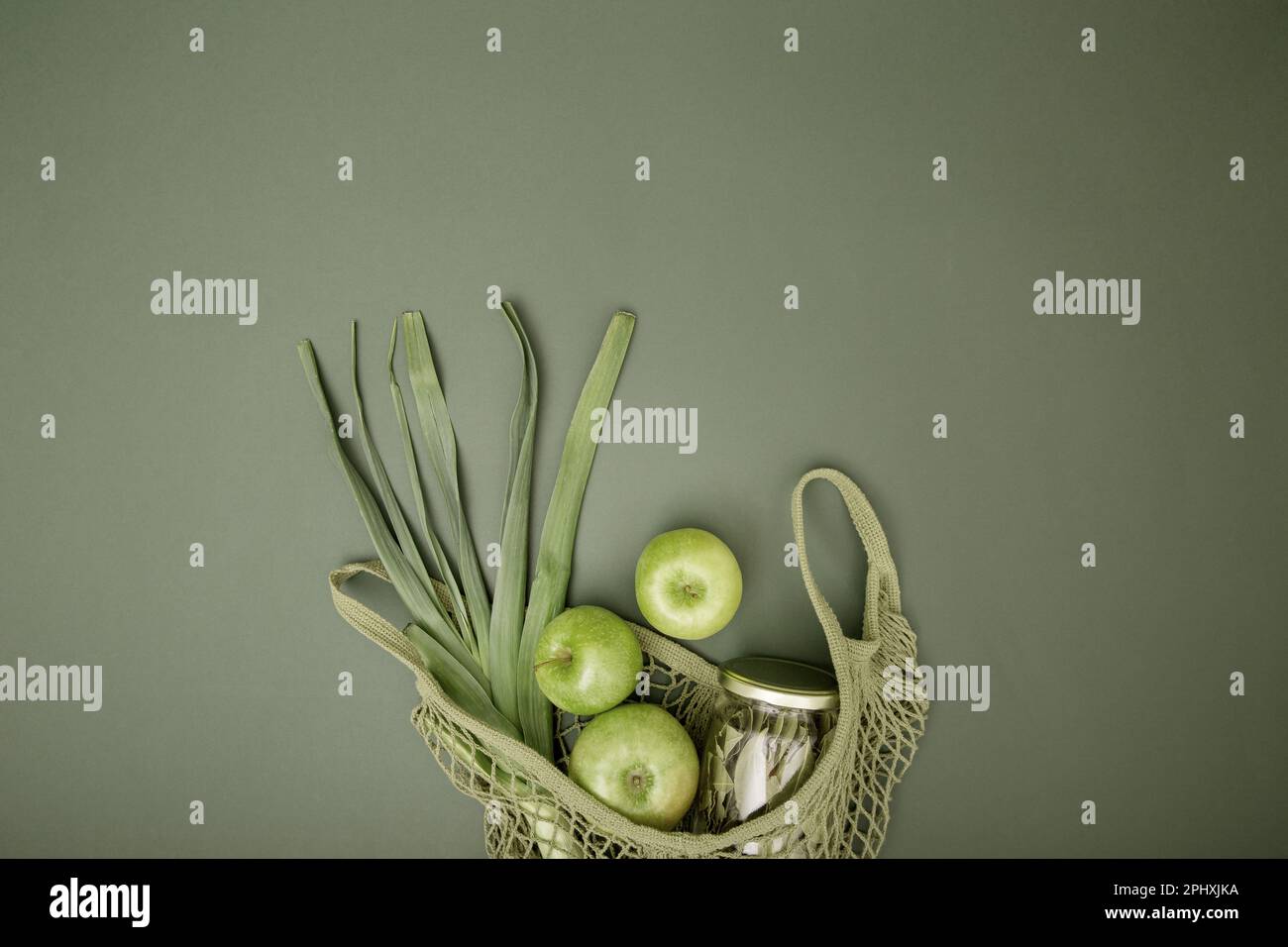 Green apples, leek and bay leaf in a glass jar in a shopping string bag ...