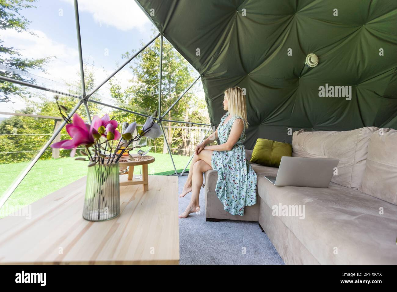 Woman working on laptop geo dome tents. Green, blue background. Cozy, camping, glamping, holiday ...