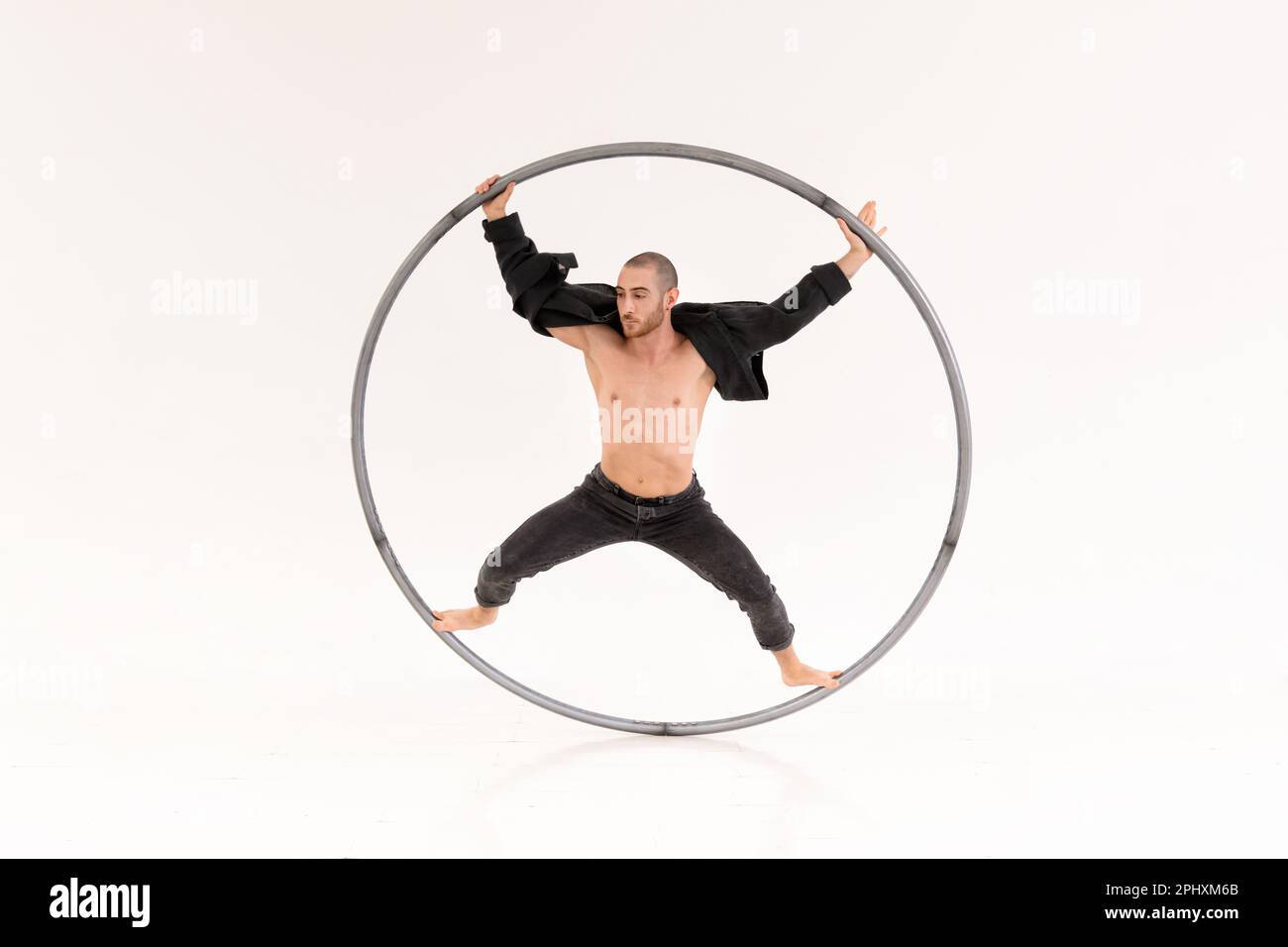 Full body of concentrated male cyr wheel artist performing trick in ...