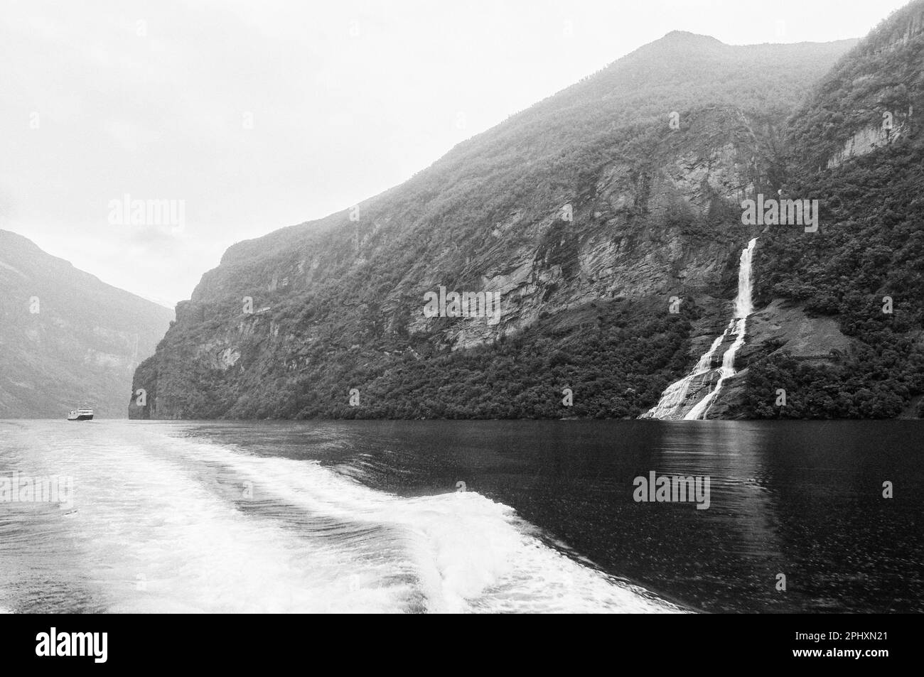 boat sailing in a fiord in Norway with waterfalls falling down the ...