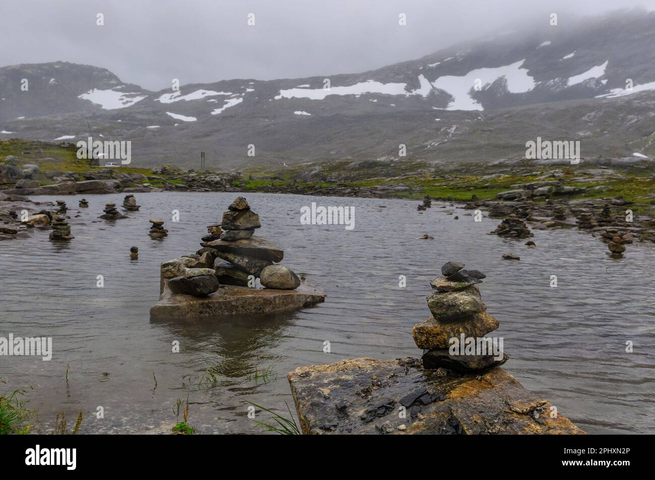 milestones in the water in a lake in Norway with snow in the mountains ...
