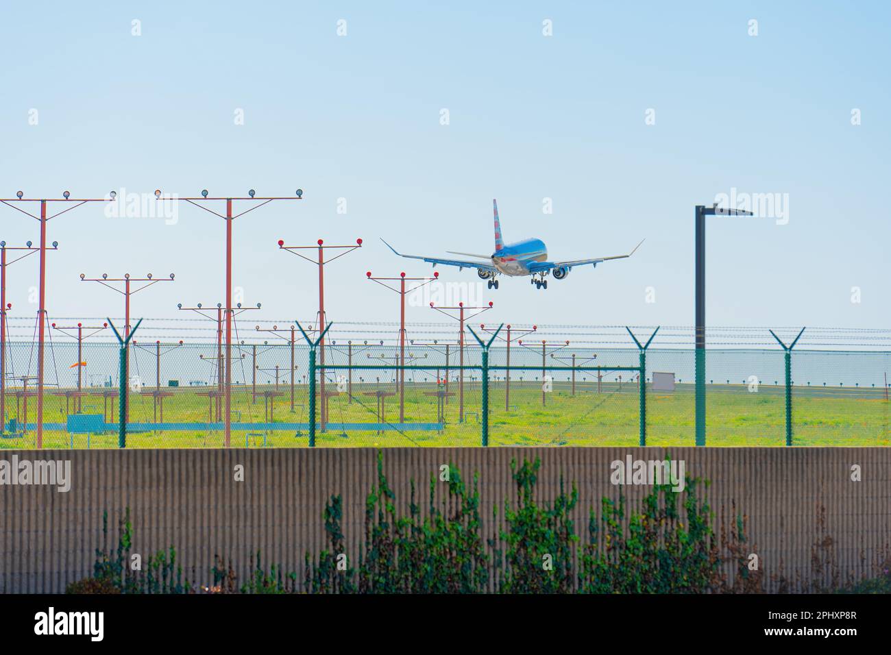 Close-up view of an airplane landing against a backdrop of light poles ...