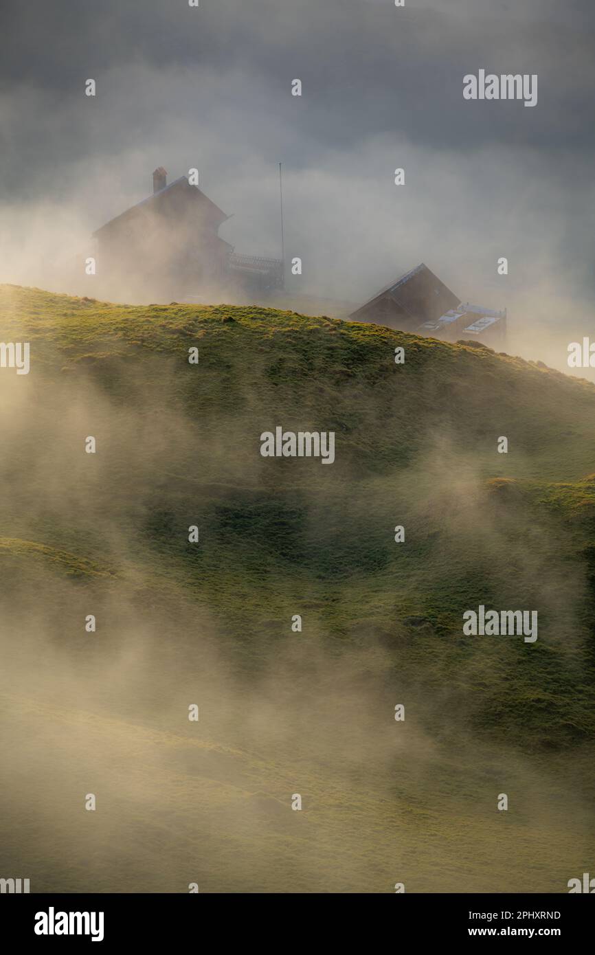 Green hilly landscape with a farm shrouded in mist Stock Photo - Alamy