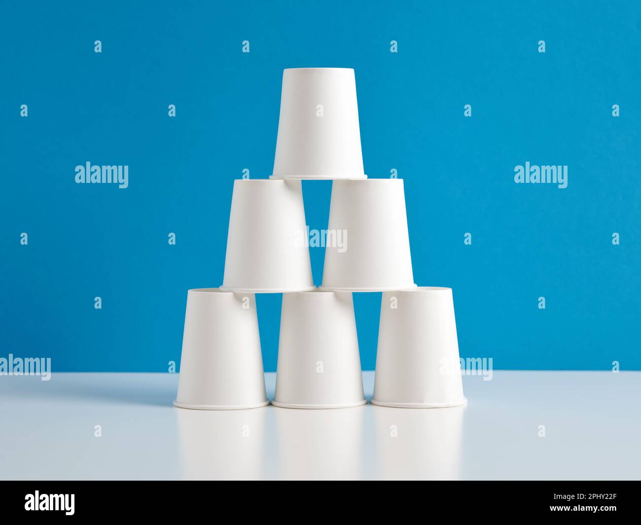 Pyramid of white paper cups on blue background Stock Photo - Alamy