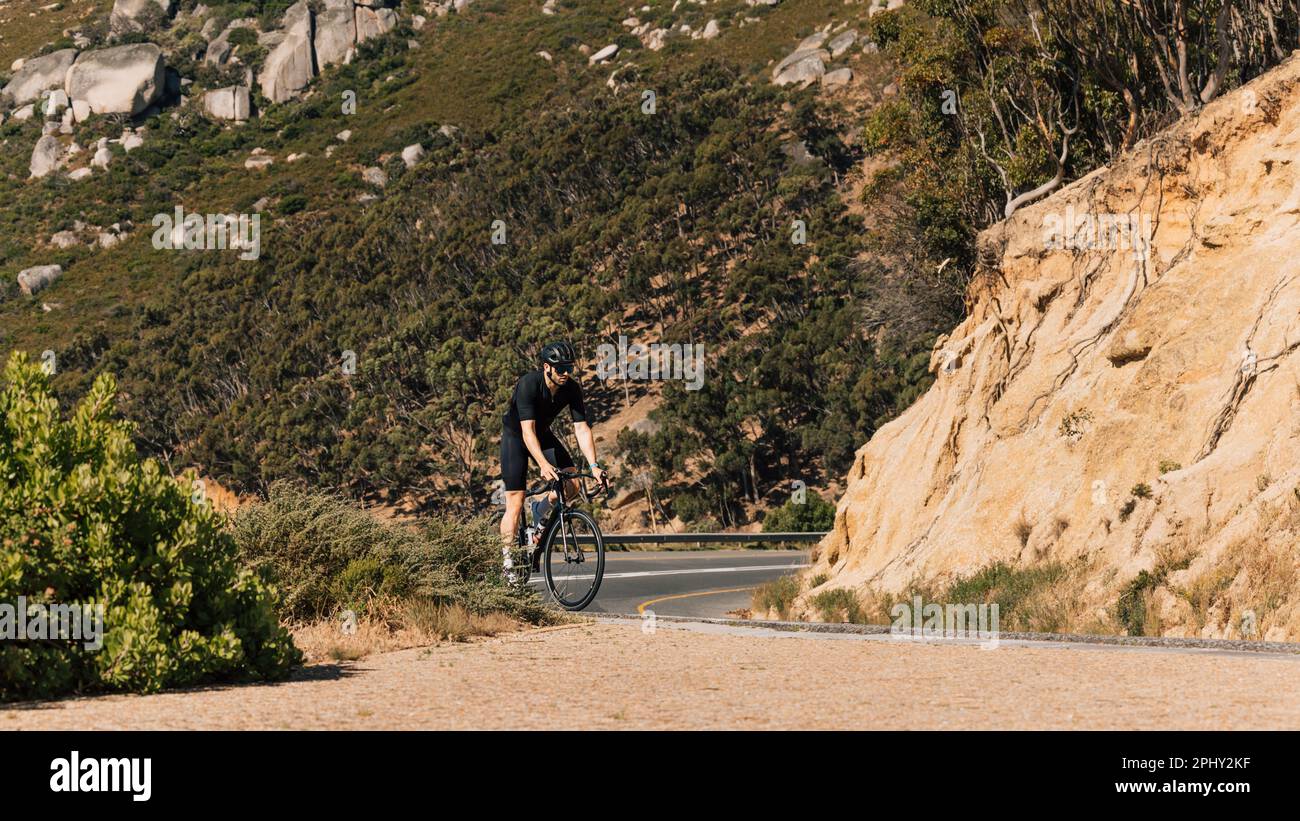 Professional male cyclist on a road bike in wild terrain Stock Photo ...