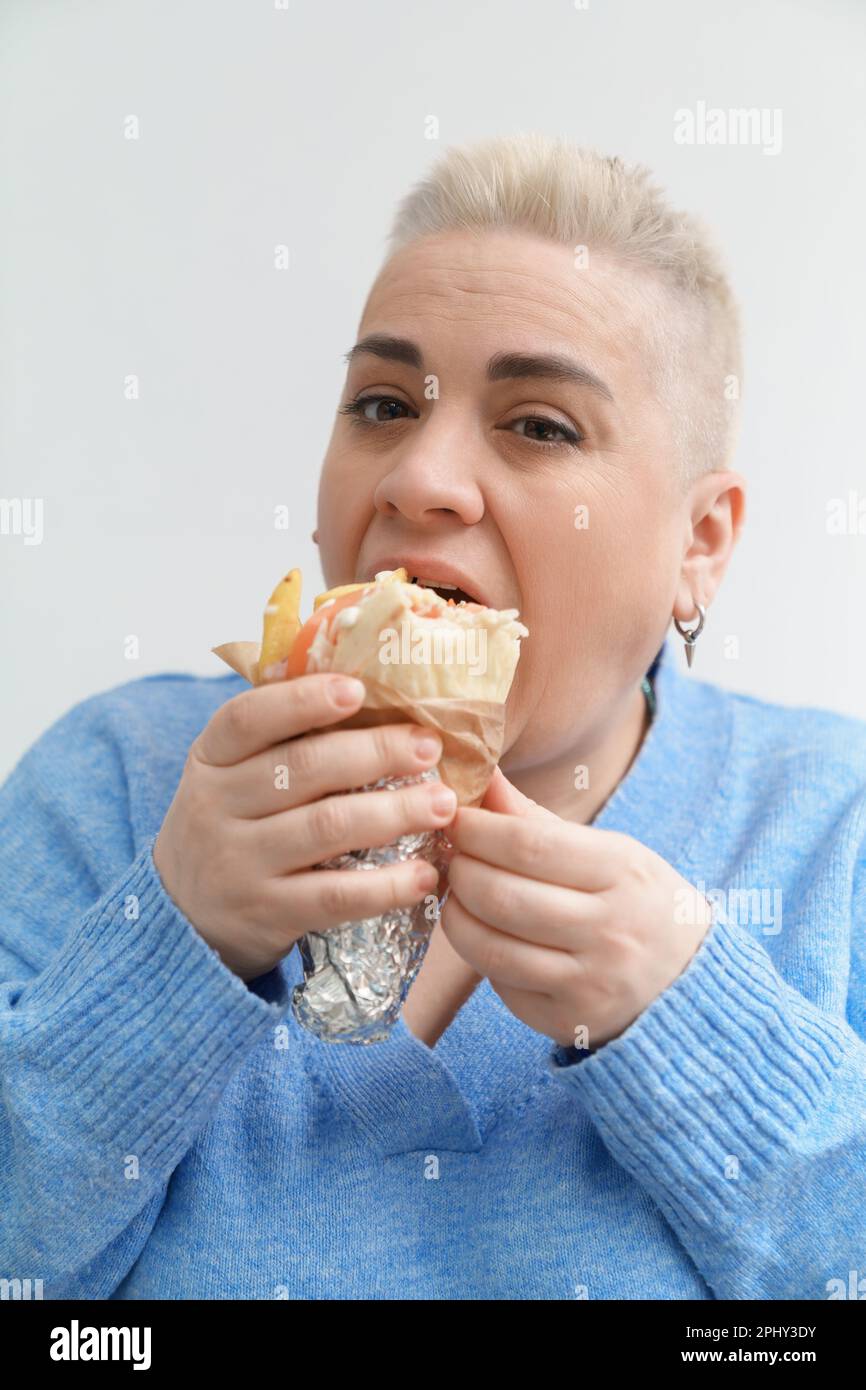 White woman with short hair enjoying Greek gyro sandwich. Portrait of a ...