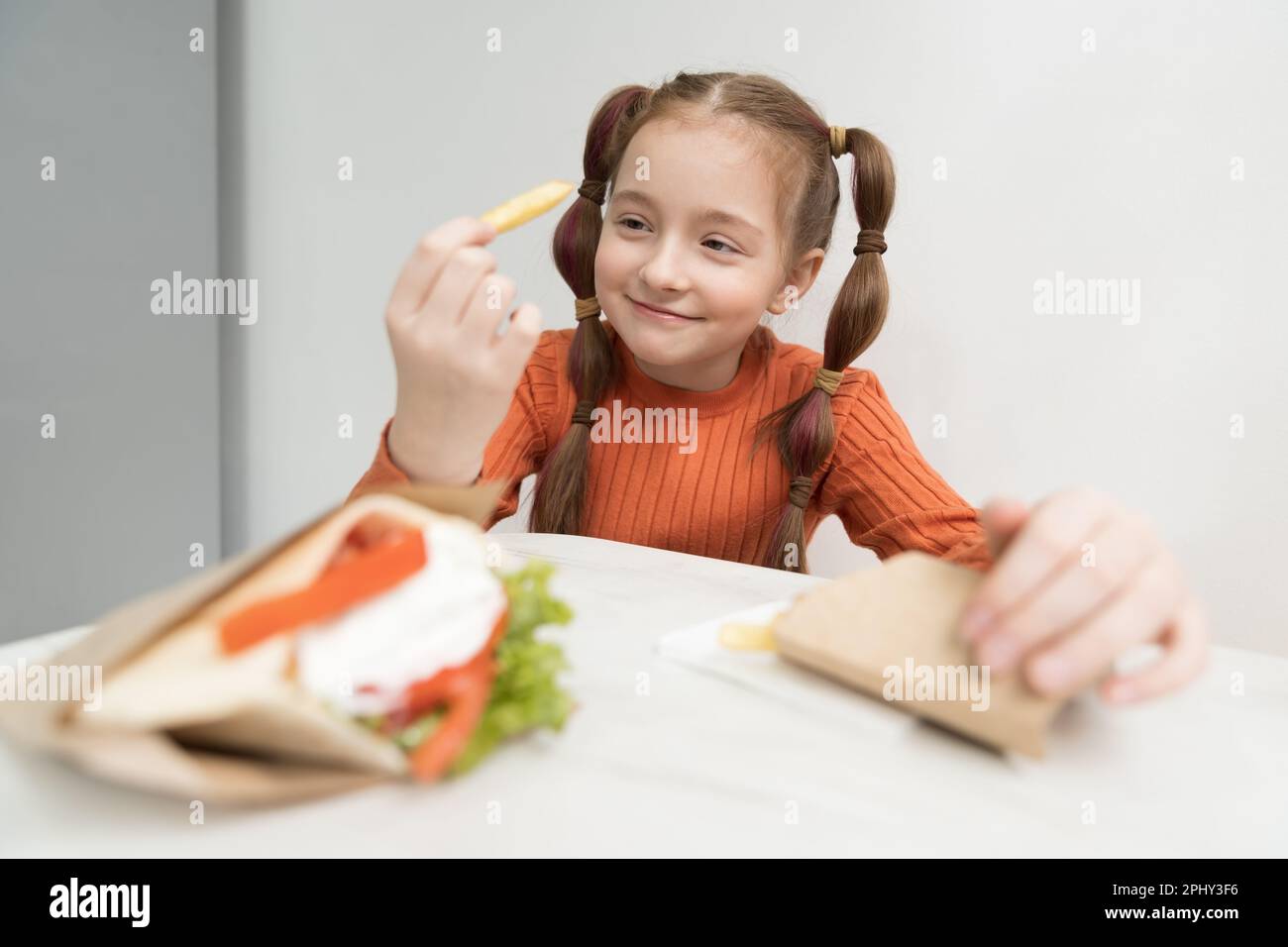 Cute little girl eats fries and gyros pita sandwich in a Greek ...