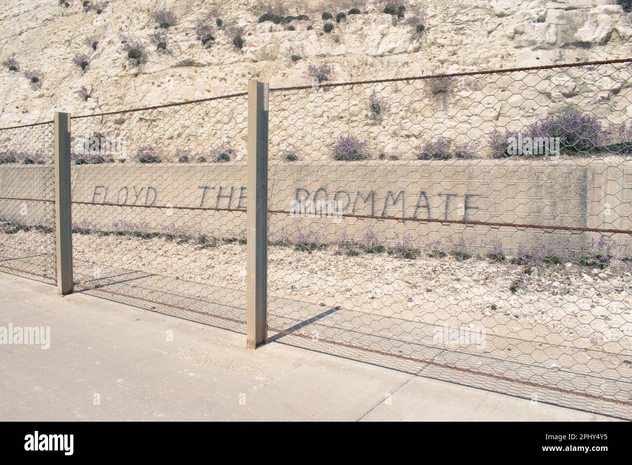 Graffiti on wall behind fence on Brighton under cliff Stock Photo - Alamy