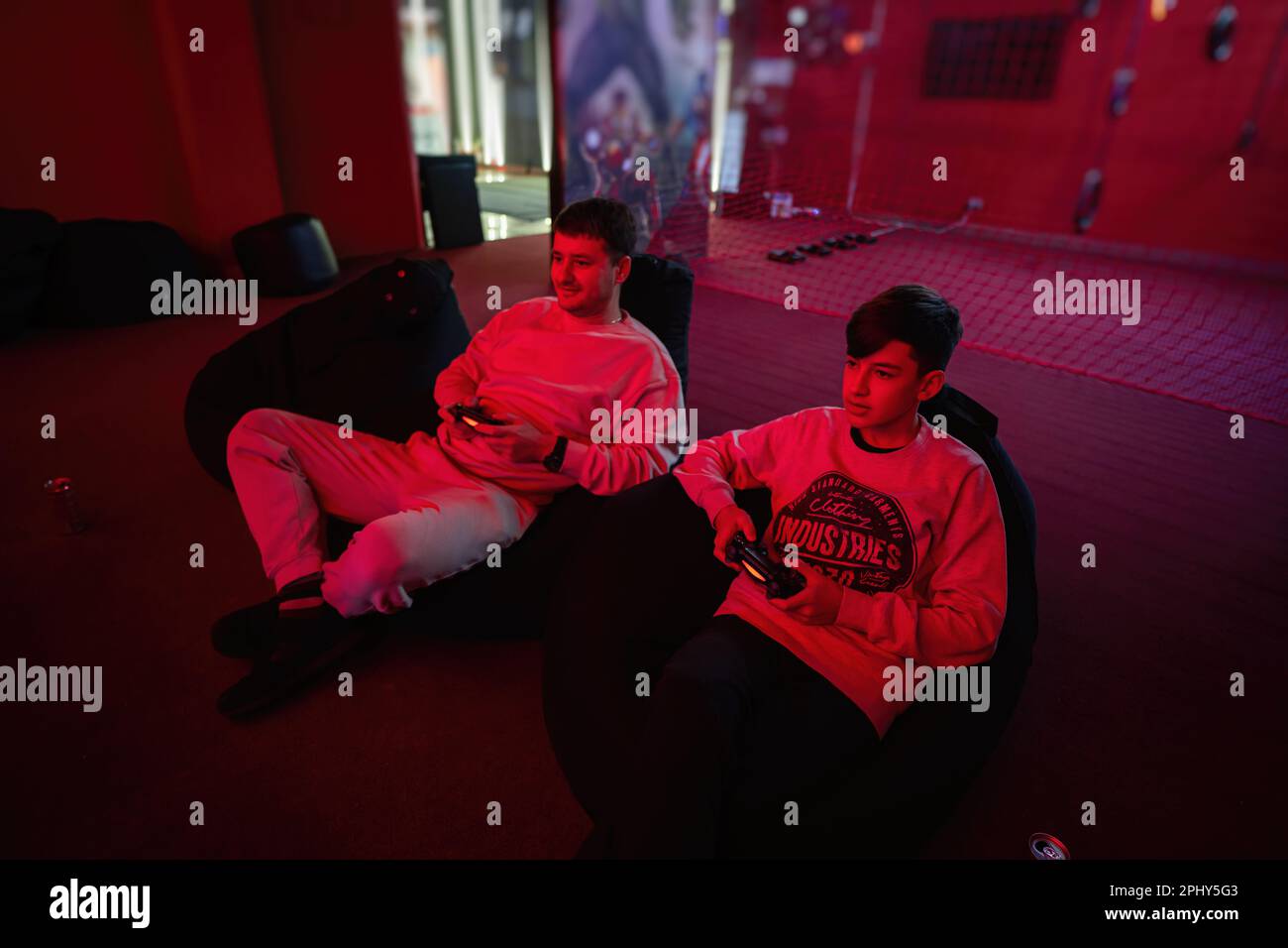 Father and son play gamepad video game console in red gaming room. Dad ...