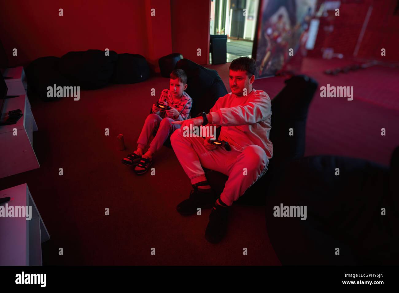 Father and son play gamepad video game console in red gaming room. Dad ...