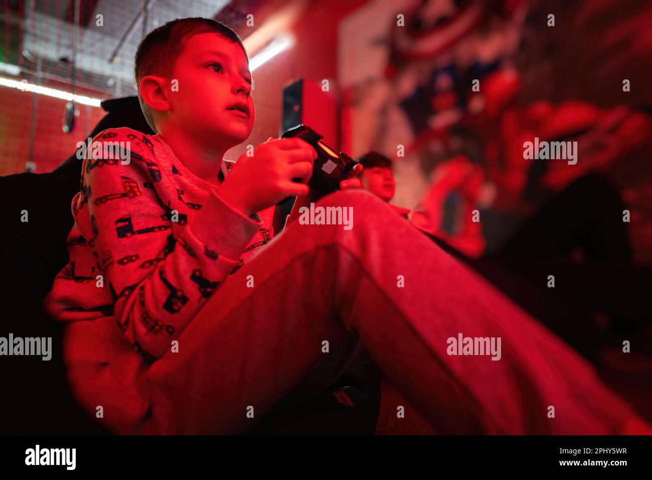 Two boys gamers play gamepad video game console in red gaming room ...