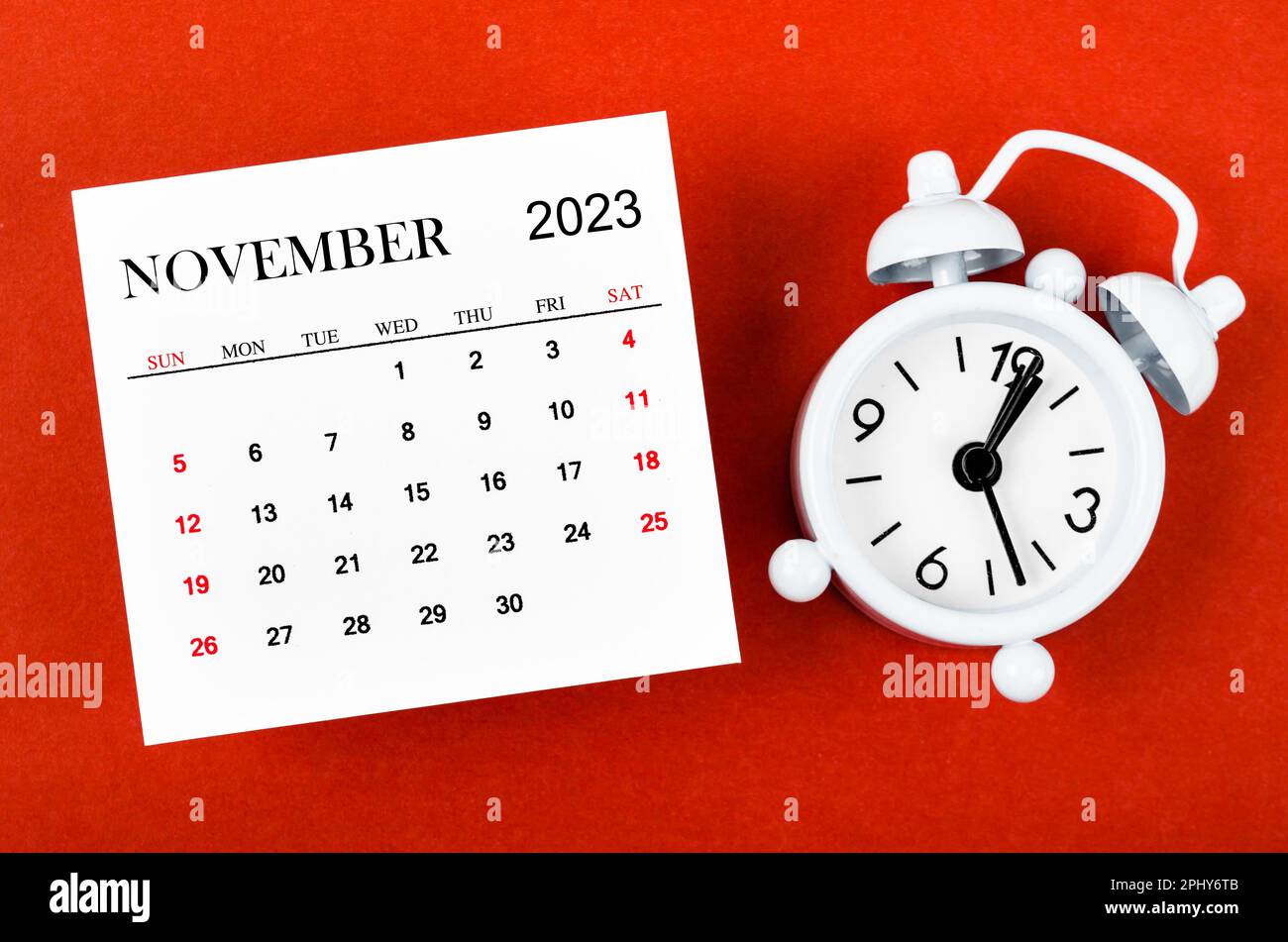November 2023 Monthly calendar year with alarm clock on red background ...