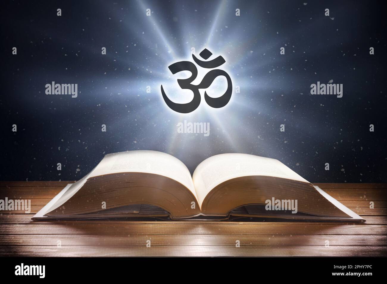 Open book on wooden table and hindu symbol with beam of light with dark ...
