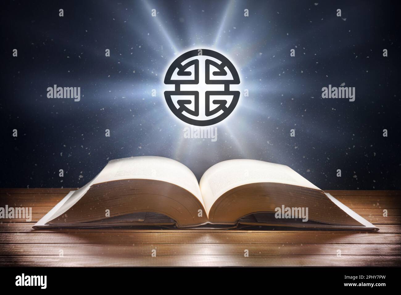 Open book on wooden table and shenism symbol with beam of light with ...