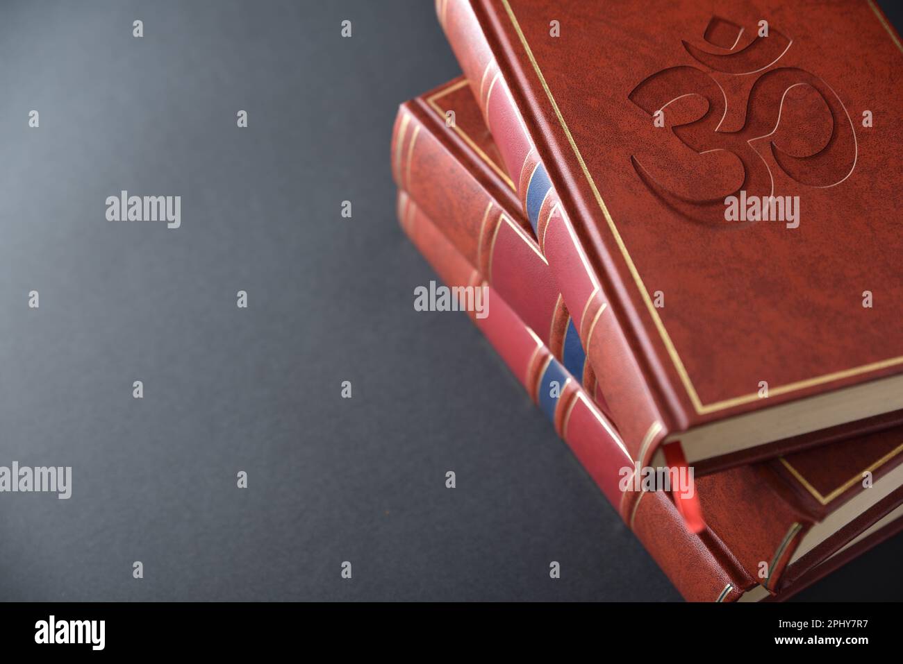 Stack of books with brown leather cover with engraved symbol of hindu ...