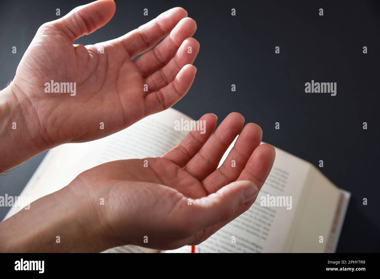 Religious man praying with separated hands up and religious book in the ...