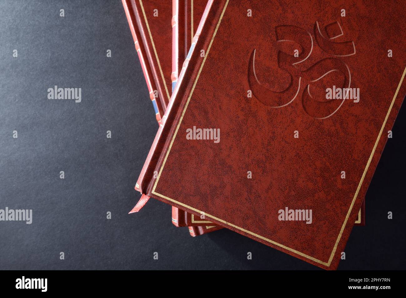Stack of books with brown leather cover with engraved symbol of hindu ...