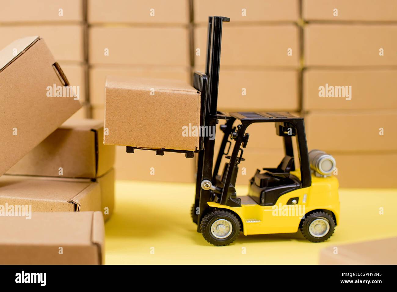 Forklift truck raises cardboard boxes on a yellow background. Cargo ...