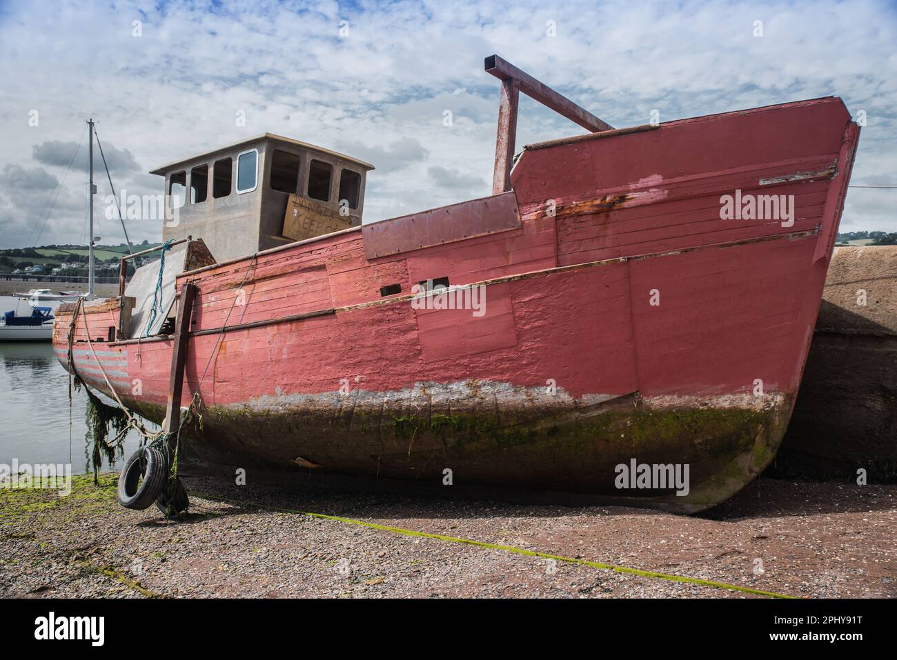 An old pink fishing boat beached at low tide in Teignmouth, Devon ...