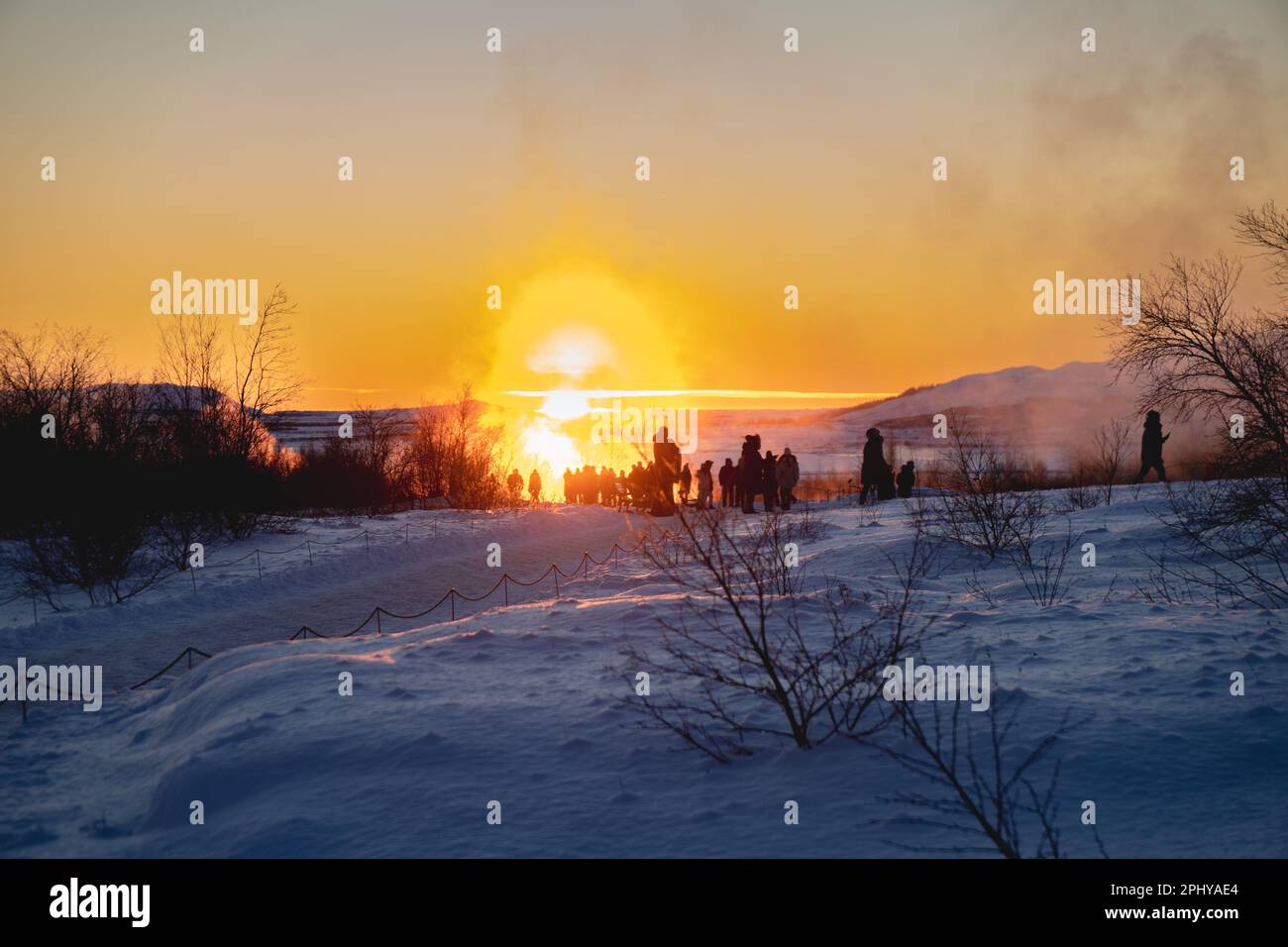 Silhouettes of tourists backlit in the setting sun at Strokkur geyser ...