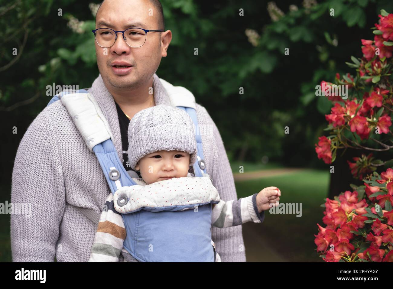 A new parent carrying his male infant with a baby carrier walking in ...