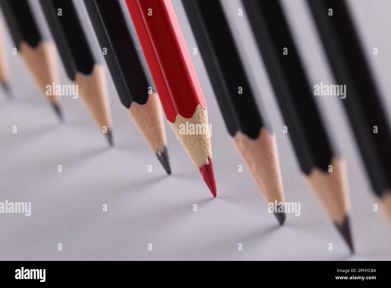 Sharp red pencil stands out from identical black pencils on gray ...