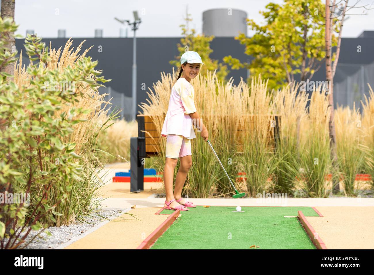 Cute preschool girl playing mini golf with family. Happy child having ...
