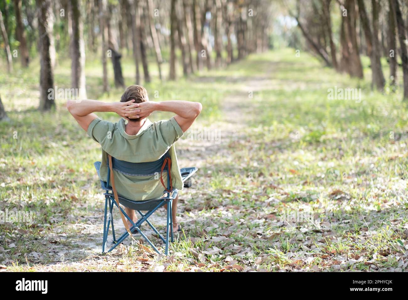 Back view on young man enjoing sunlight in green summer park. Relaxing ...