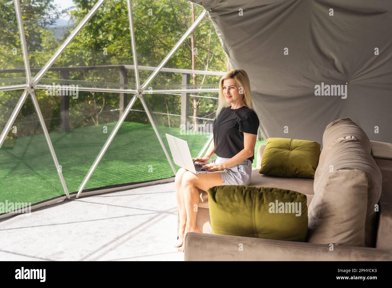 Woman working on laptop geo dome tents. Green, blue background. Cozy, camping, glamping, holiday ...