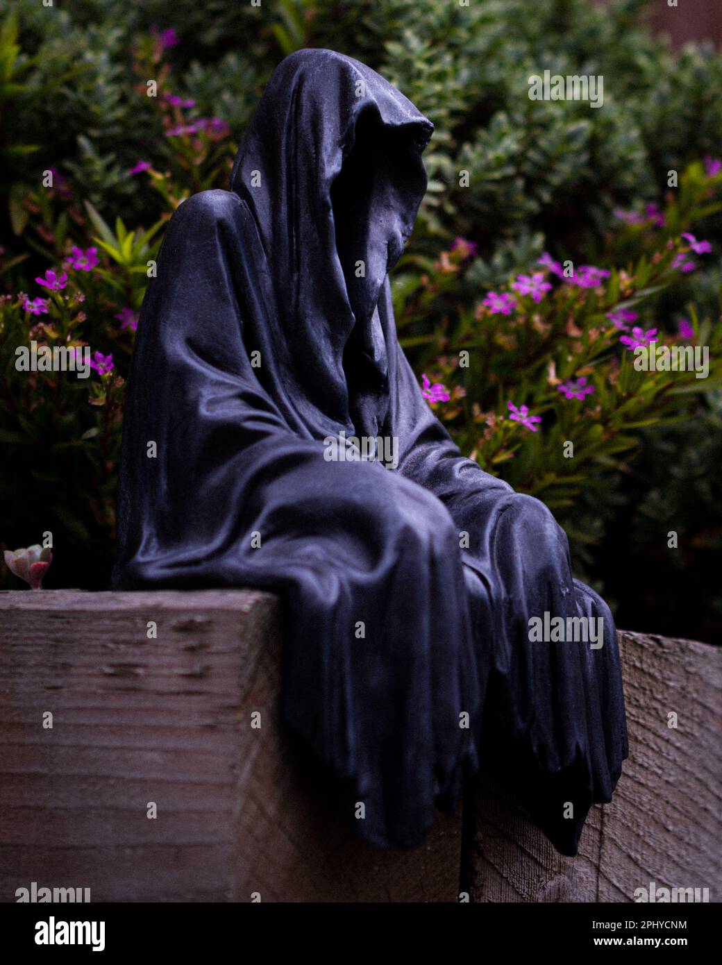 A menacing statue of the Grim Reaper, cloaked in a long, flowing robe ...