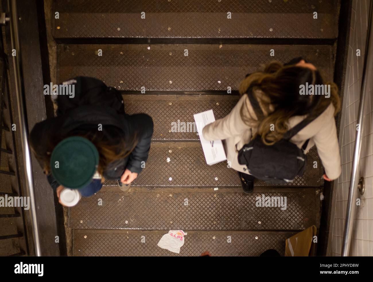 An aerial view of two women ascending and descending a staircase, each in a different direction ...