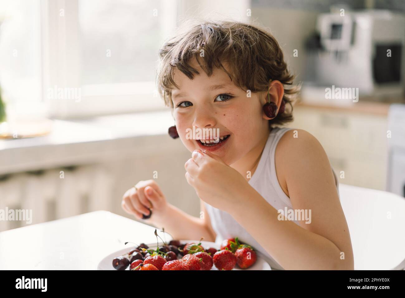 Cute beautiful little boy eating fresh cherry and strawberry Stock ...