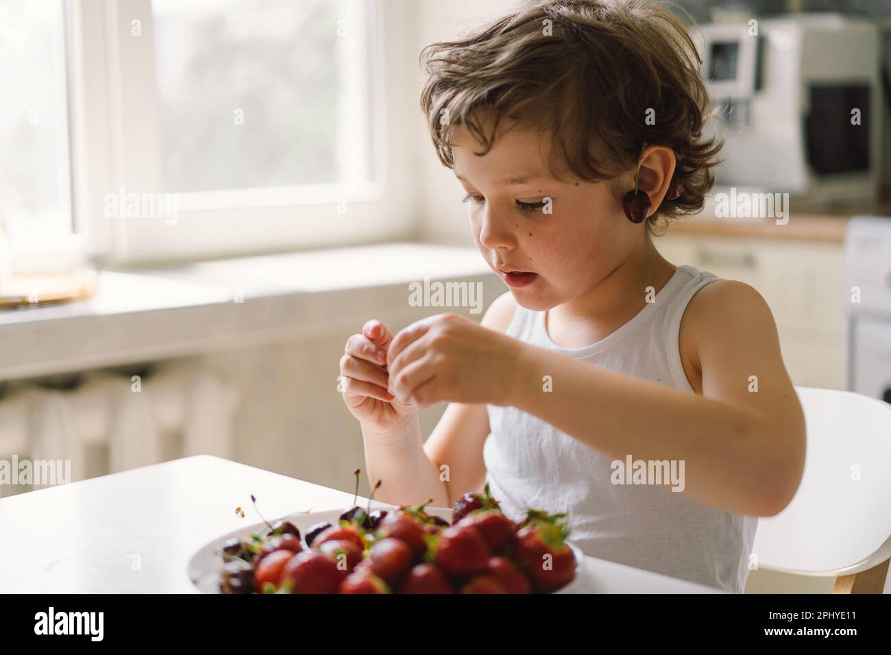Cute beautiful little boy eating fresh cherry and strawberry Stock ...