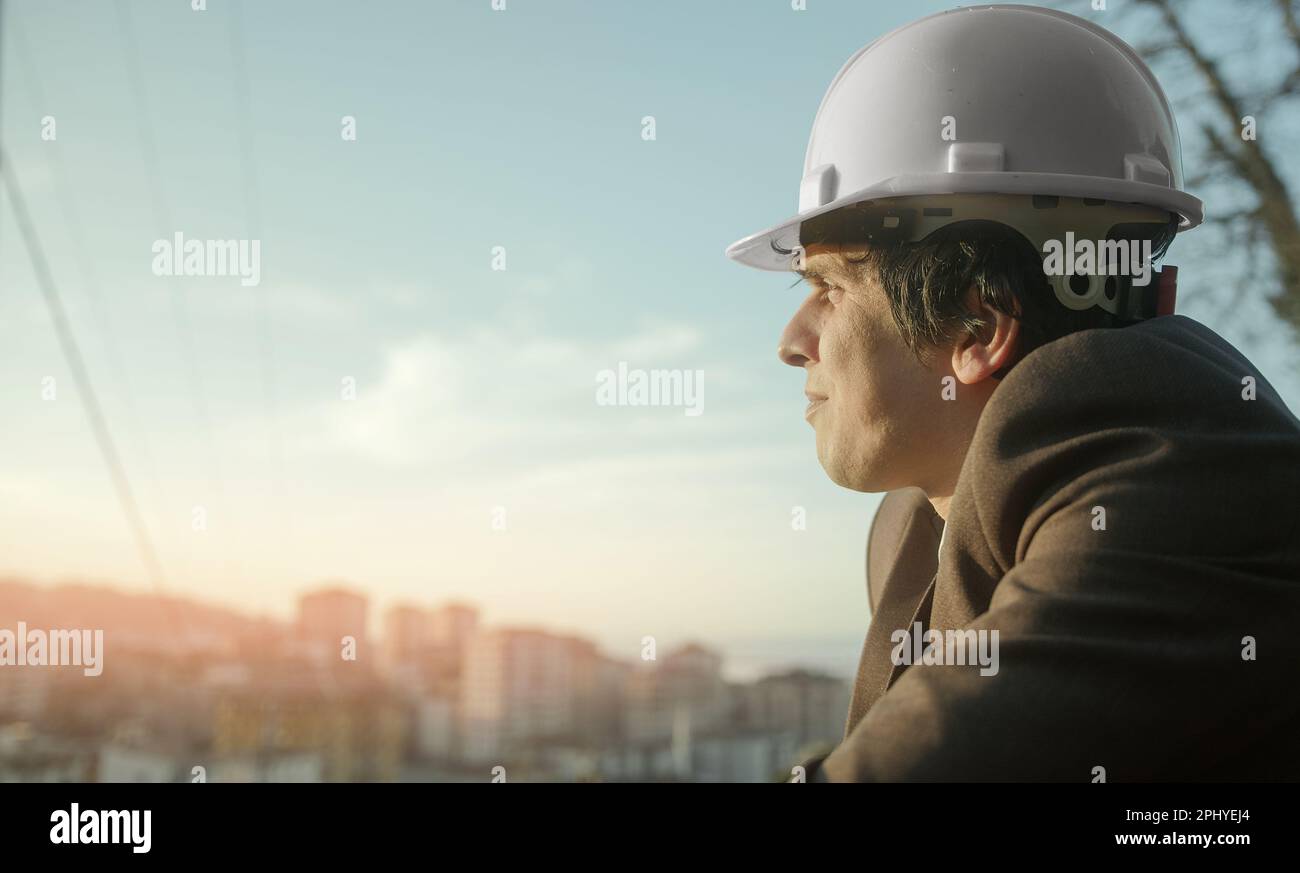 Civil engineer, wearing a hard white hat and suit, decides with a smile ...